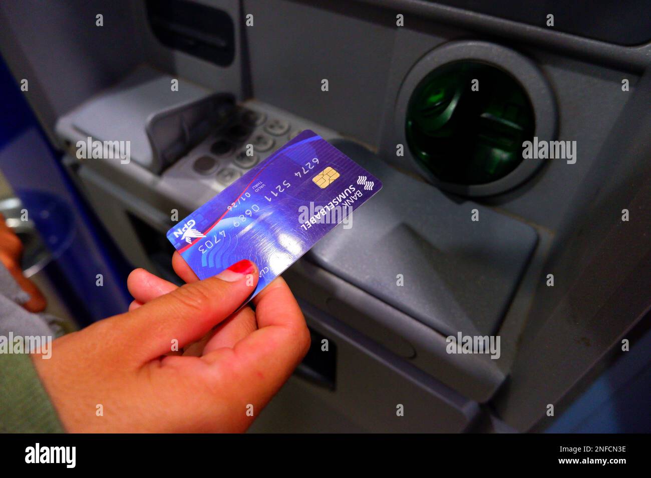 A Woman's Hand Is Holding A Card For A Transaction At An Atm Machine At ...