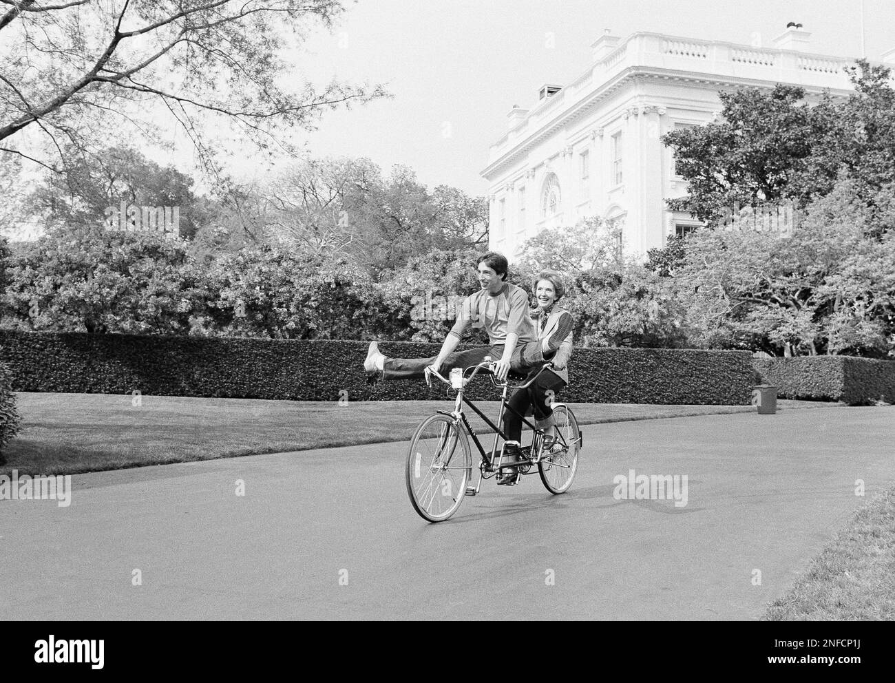First lady Nancy Reagan takes a ride on a bicycle built for two with ...