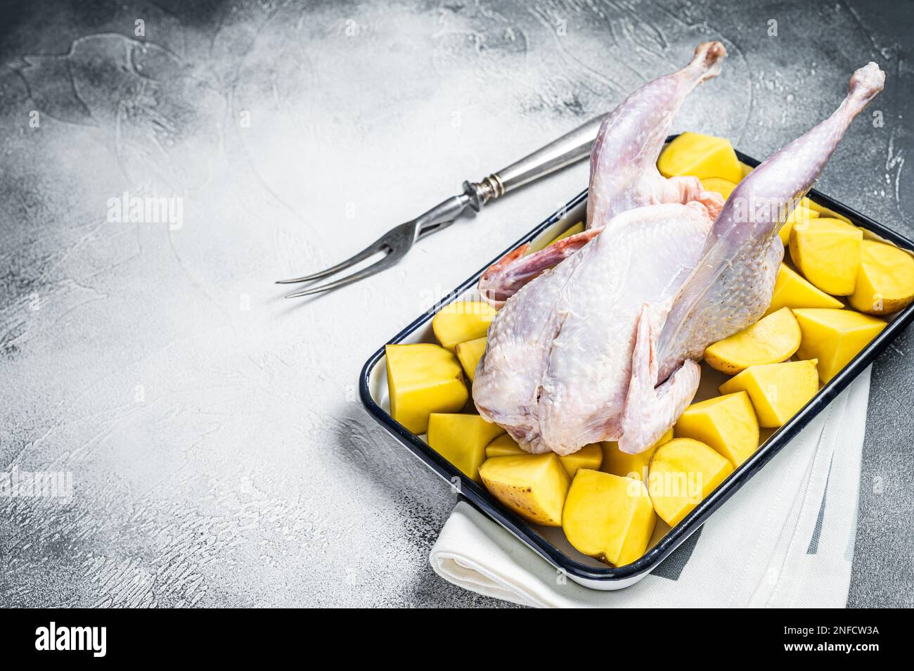 Cooking of Raw guinea fowl with potato in baking dish. White background ...
