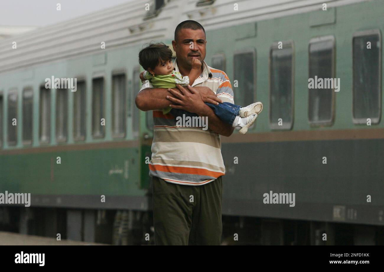 An Iraqi train pasenger walks with his daughter at al-Alawi railway ...