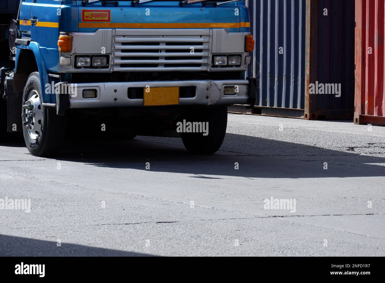 Trucks in a logistics yard with containers stacked in the background ...
