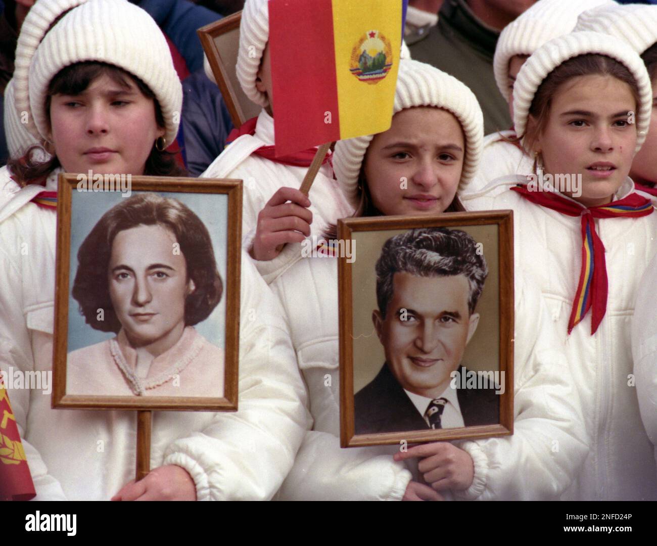 Three girls dressed in white are pictured holding framed portraits of ...