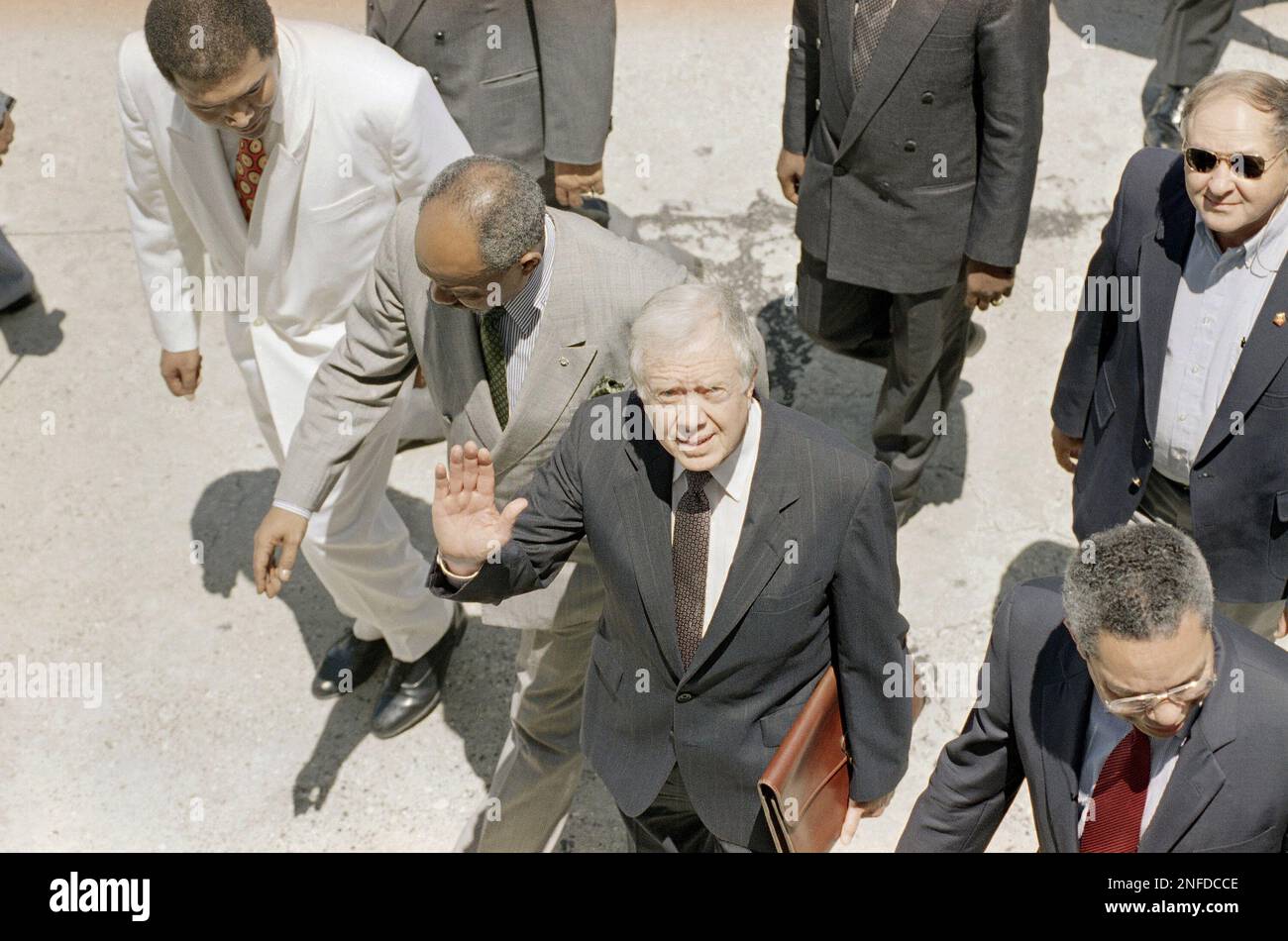 Former President Jimmy Carter waves as he walks across the runway after ...