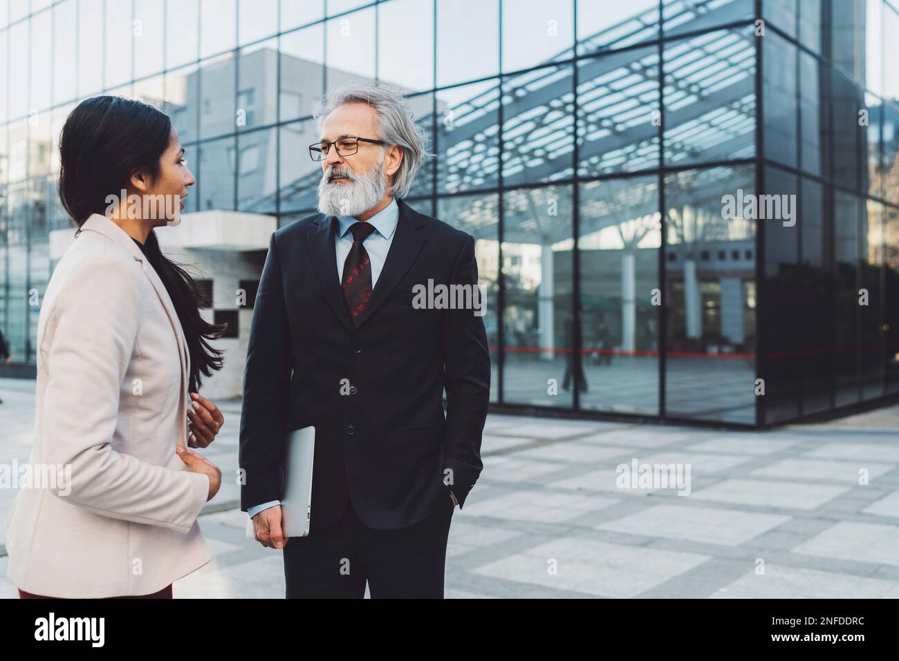 Senior business man talking to his secretary outside of the office ...