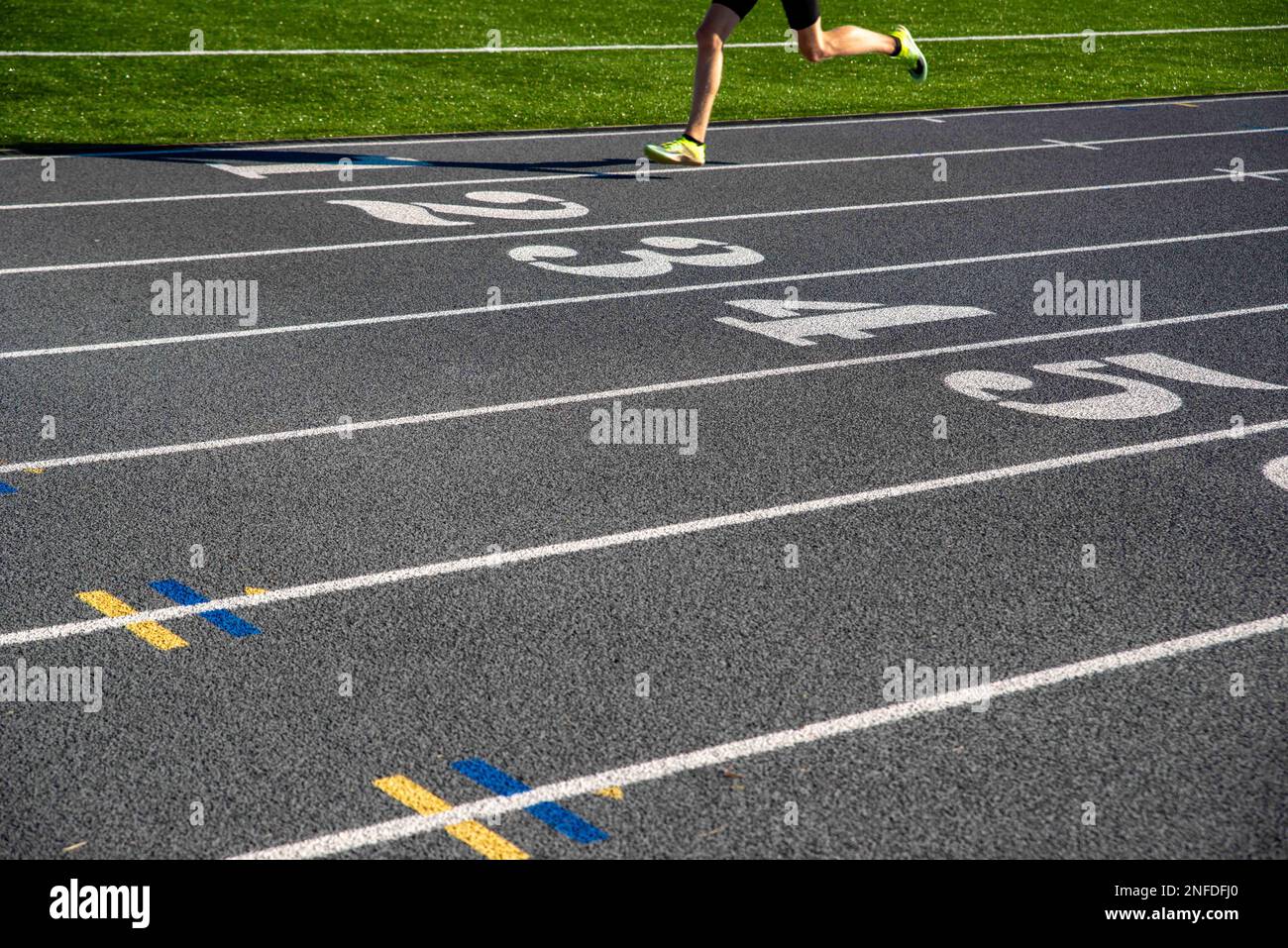 A runner on a gray athletic running track with large white numbers ...