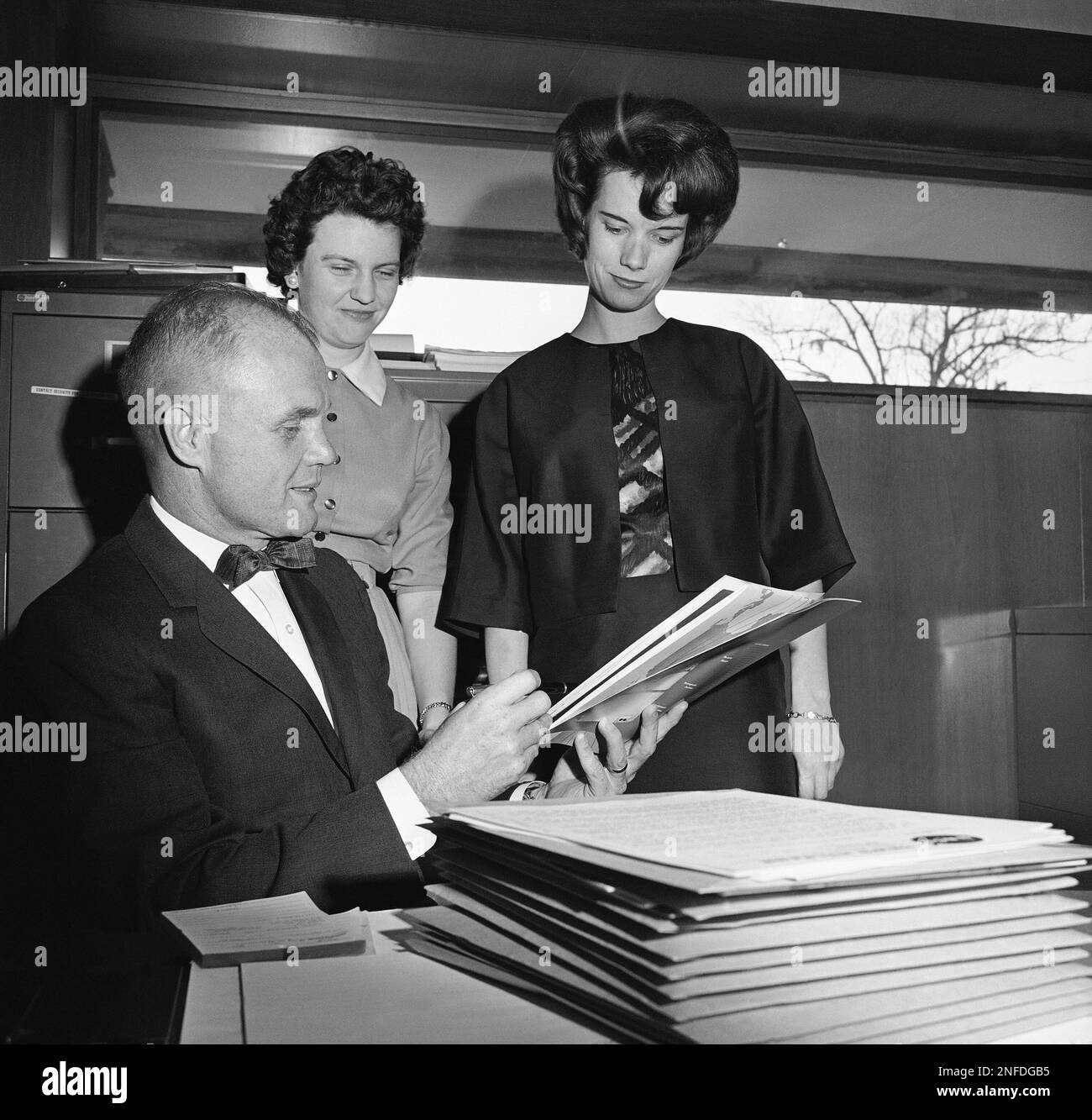 Astronaut John Glenn, left, goes over a letter with secretaries Mrs. Estelle Jackson, center ...