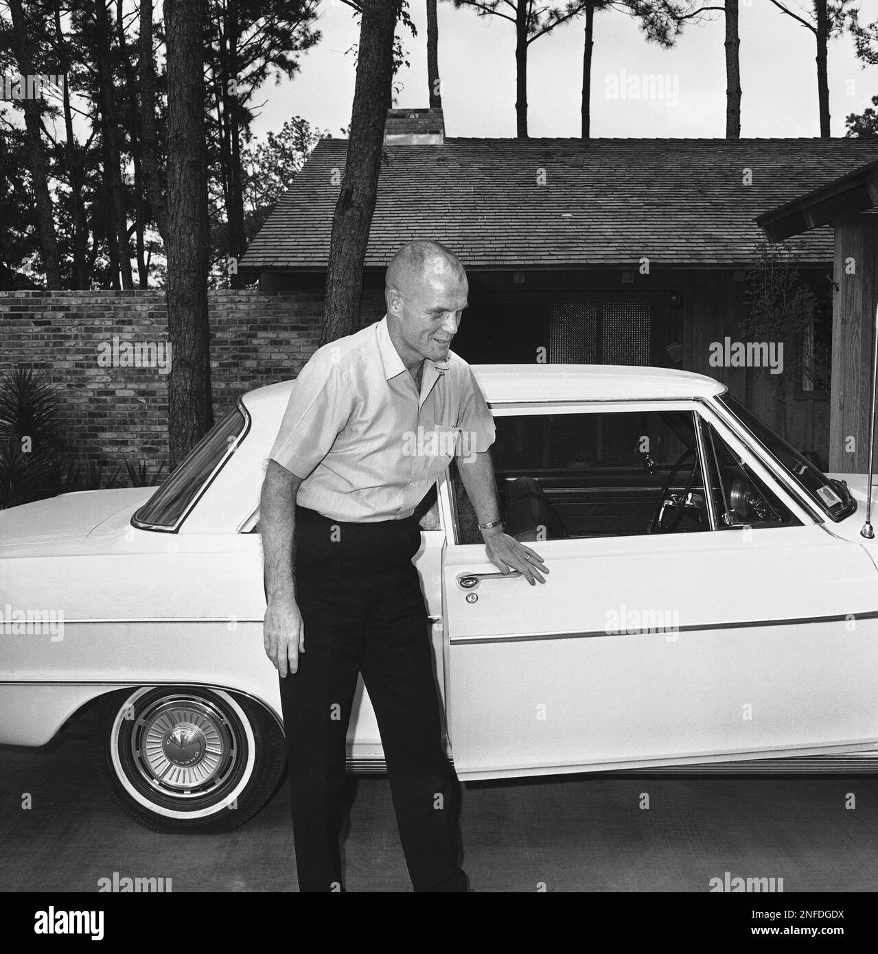 Astronaut John Glenn holds on to his car as he makes his way around the ...