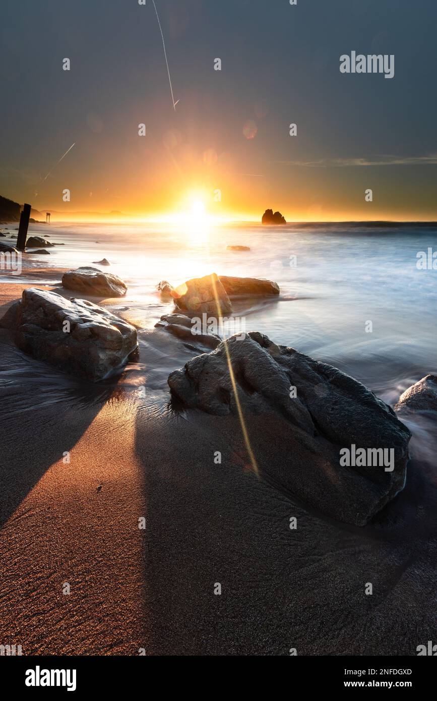 Sunset while sea waves hitting the rocks on the beach; at Ilbarritz ...