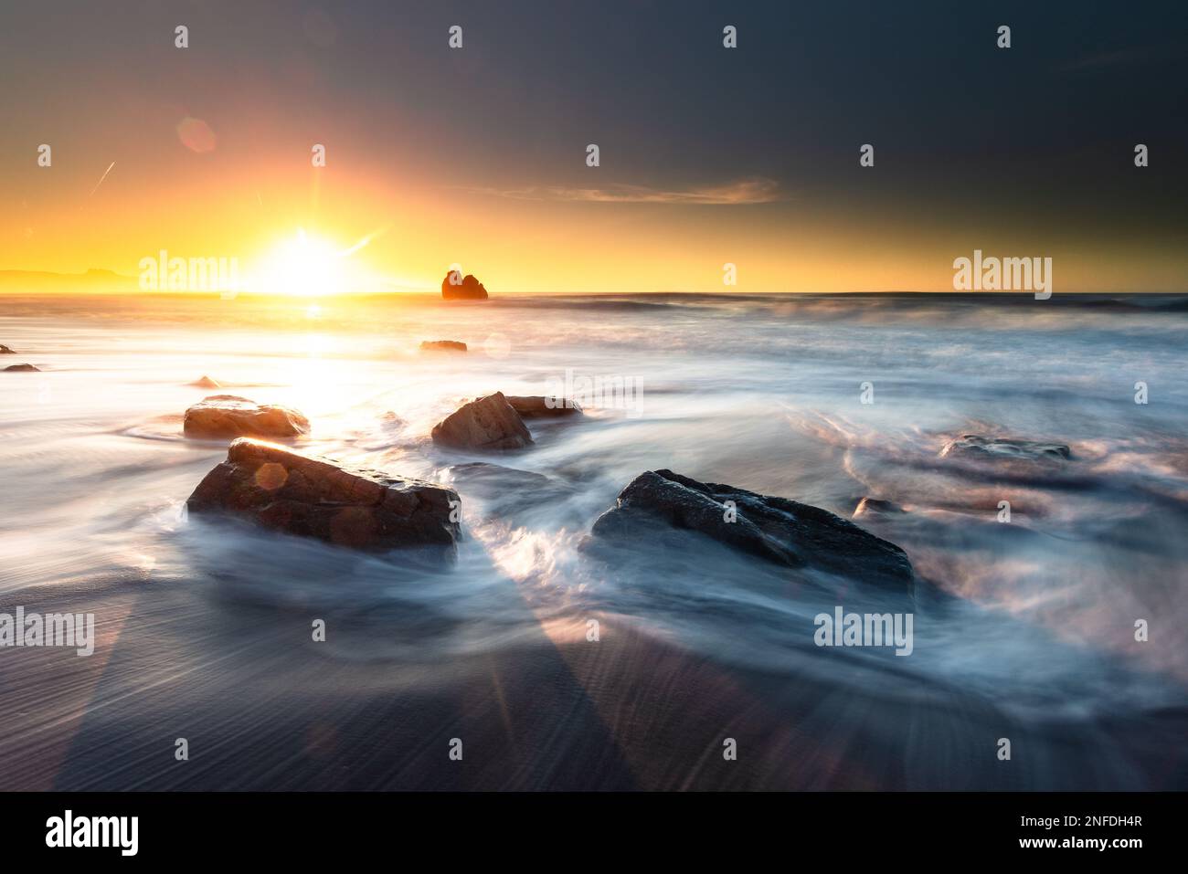Sunset while sea waves hitting the rocks on the beach; at Ilbarritz ...