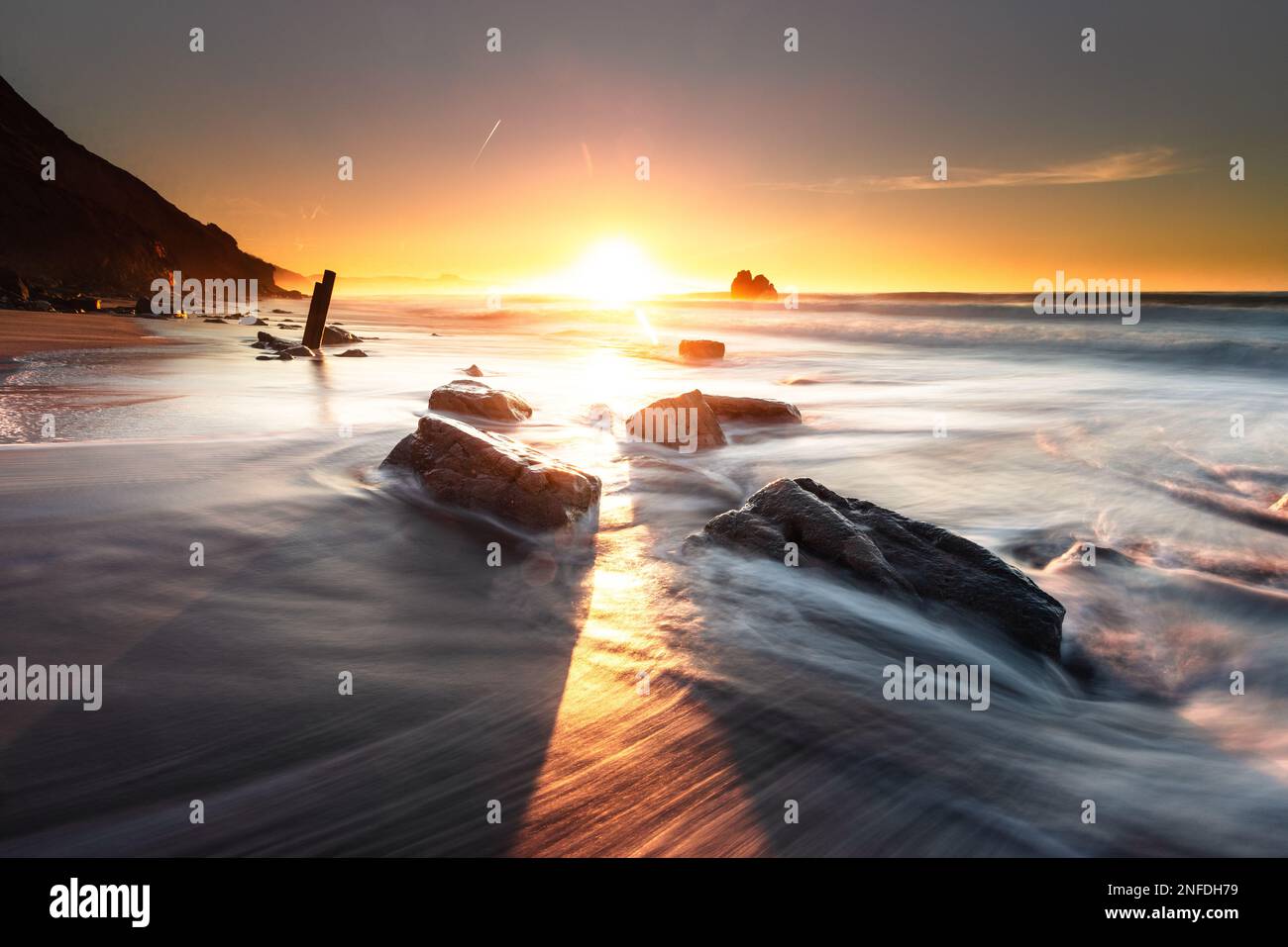 Sunset while sea waves hitting the rocks on the beach; at Ilbarritz ...