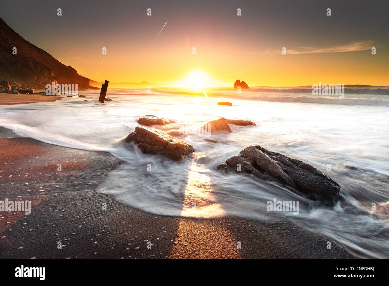 Sunset while sea waves hitting the rocks on the beach; at Ilbarritz ...