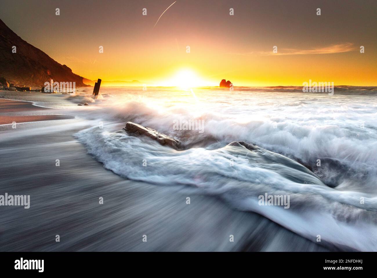 Sunset while sea waves hitting the rocks on the beach; at Ilbarritz ...