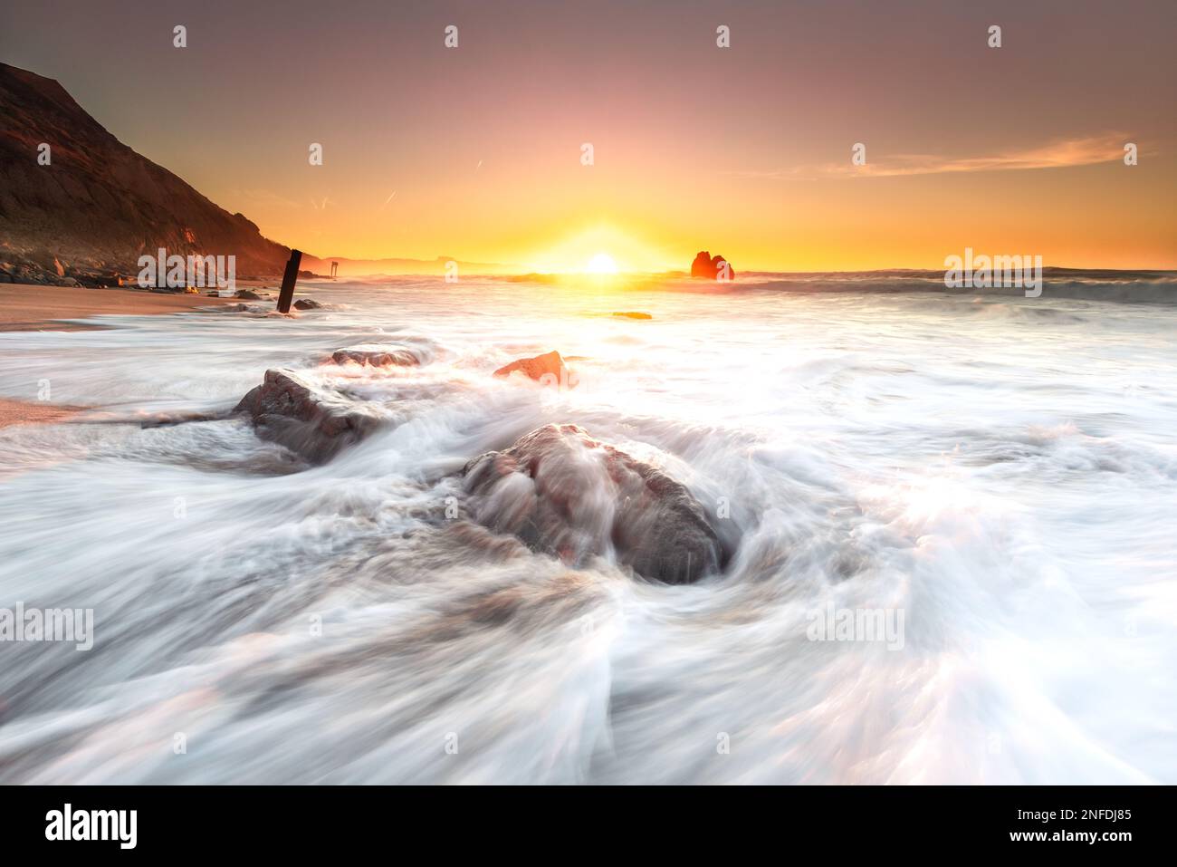Sunset while sea waves hitting the rocks on the beach; at Ilbarritz ...