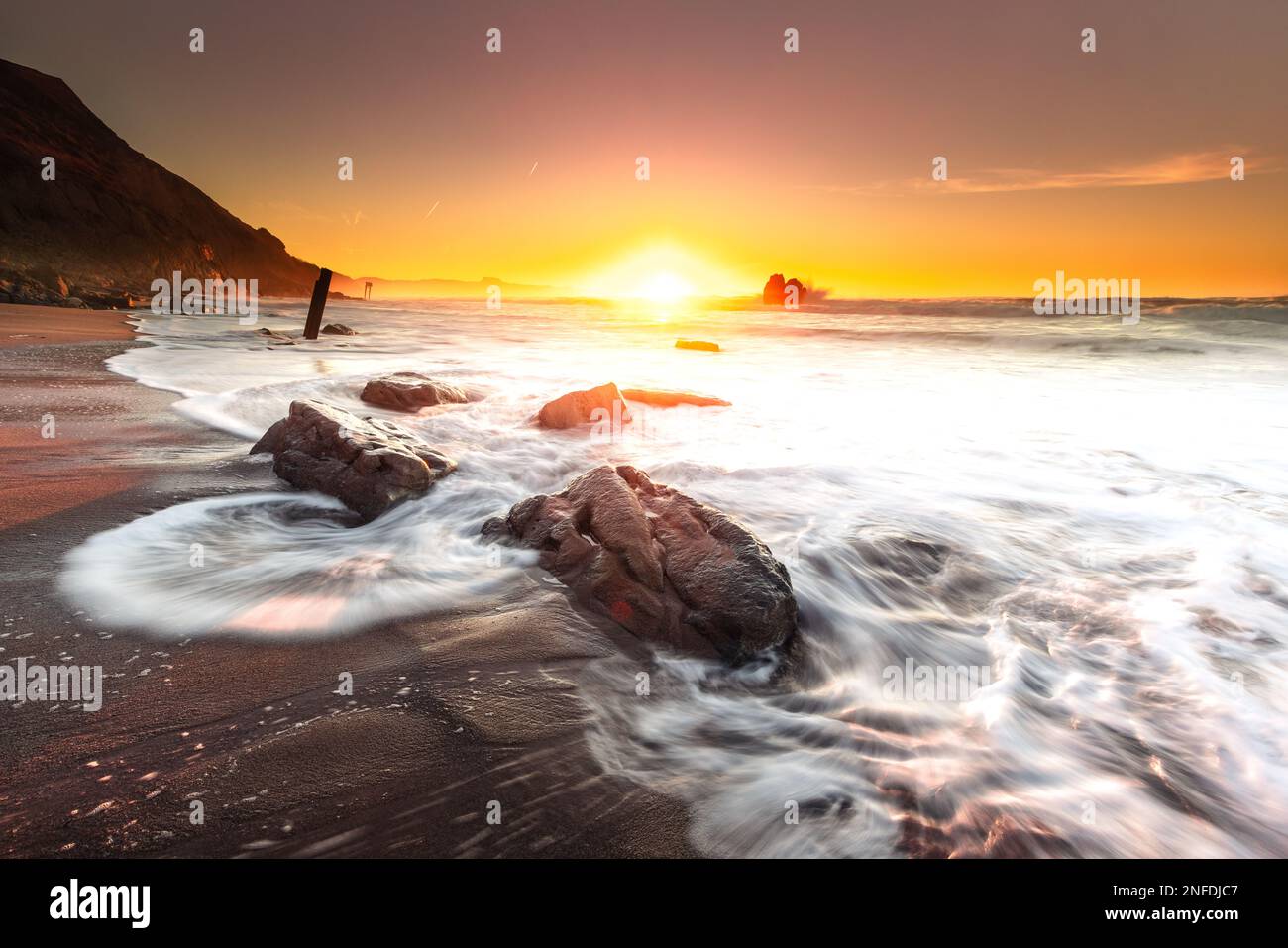 Sunset while sea waves hitting the rocks on the beach; at Ilbarritz ...