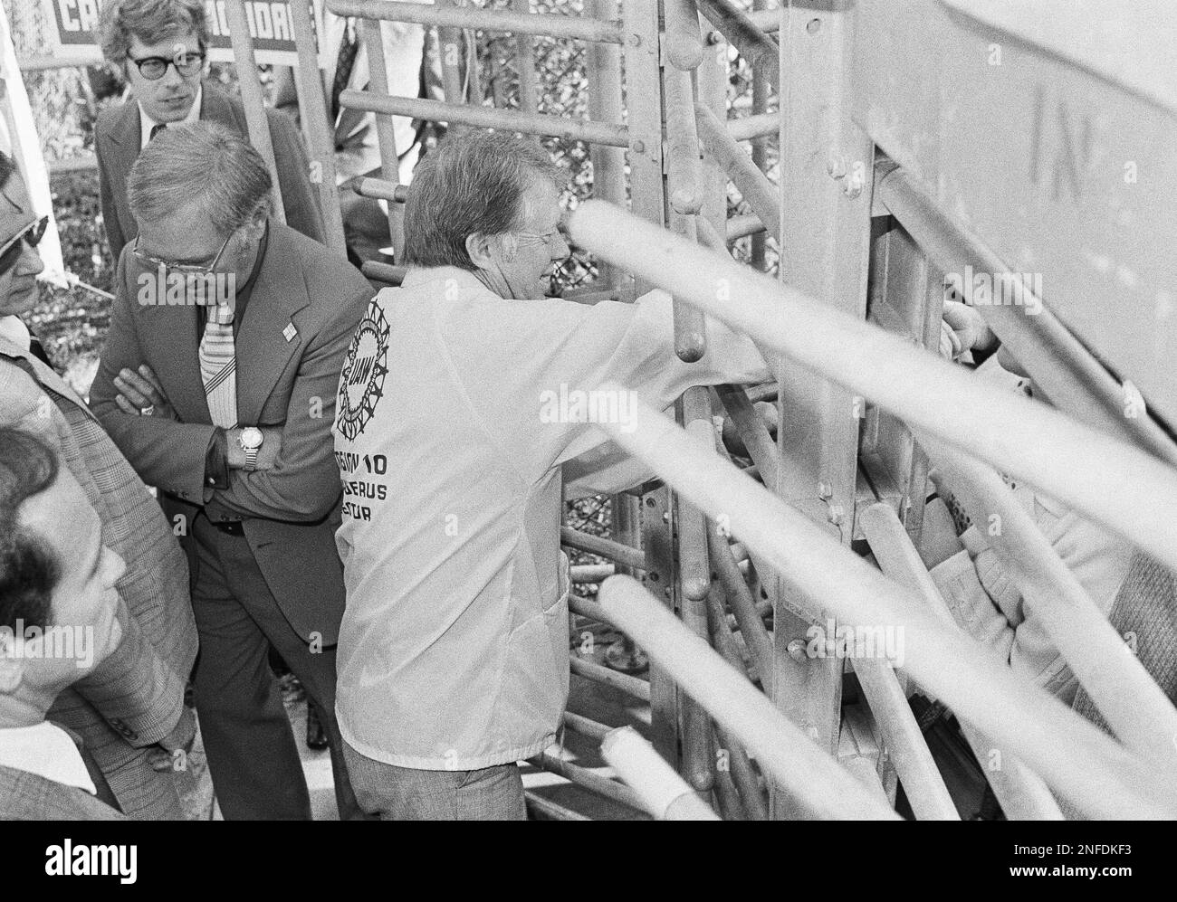 Presidential hopeful Jimmy Carter reaches through the bars of a plant ...