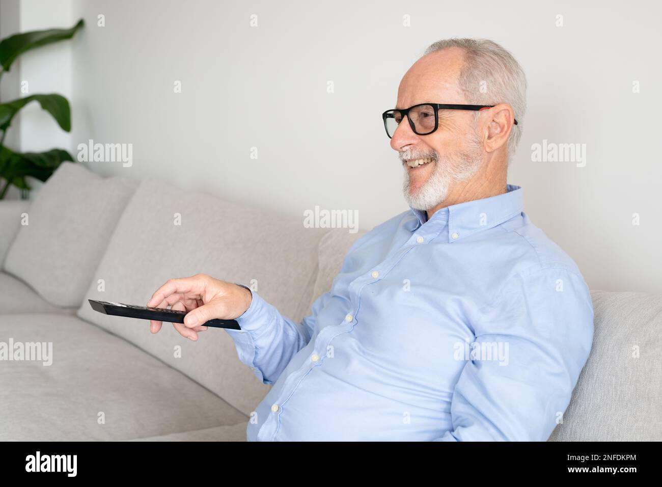 Fat senior man watching TV while sitting on sofa at home. Sedentary ...