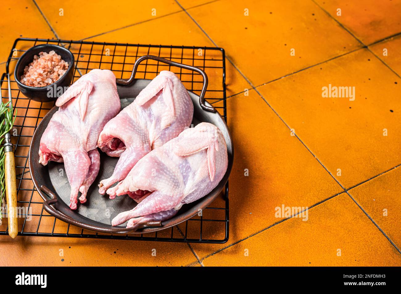 Raw whole quails ready for cooking. Orange background. Top view. Copy ...