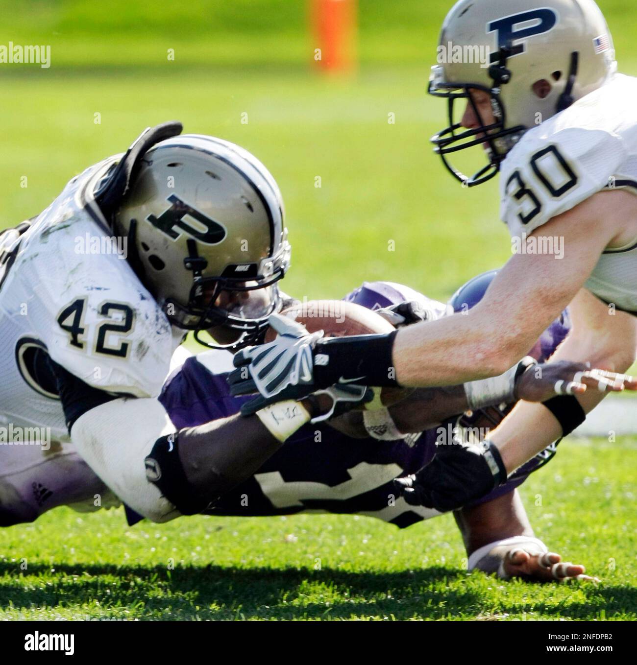 Purdue linebacker Anthony Heygood, left, and Joe Holland, right, pounce ...