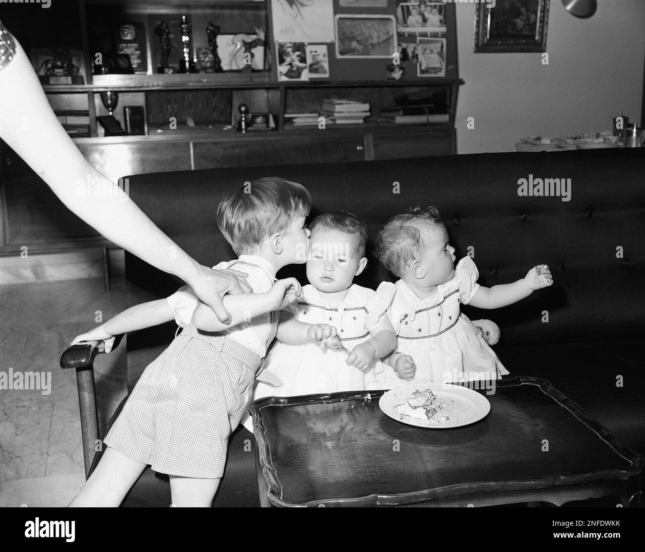 Ingrid looks away as her twin sister Isabella receives a kiss from ...