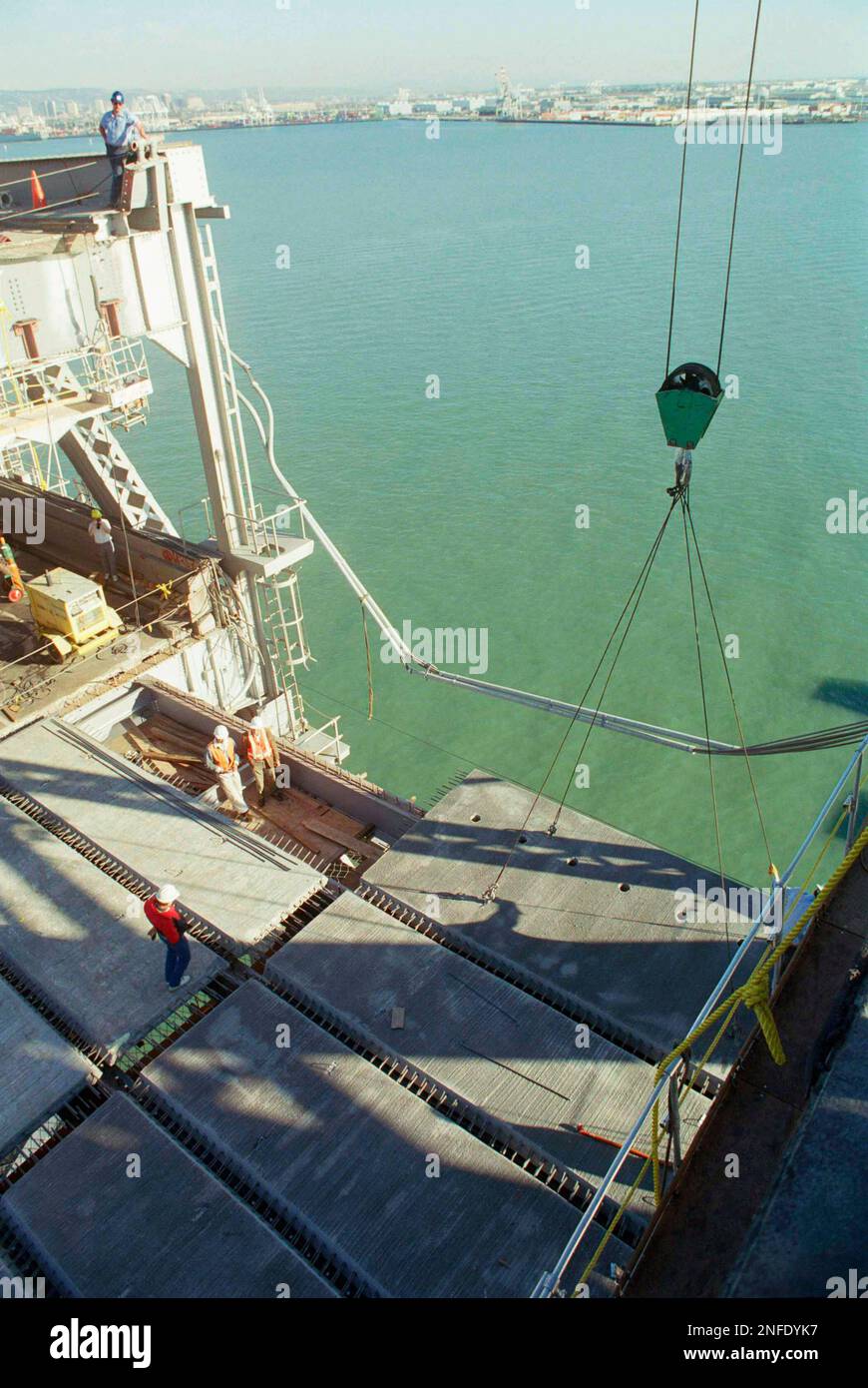 Workers add one of the last sections of the lower deck of the Bay ...
