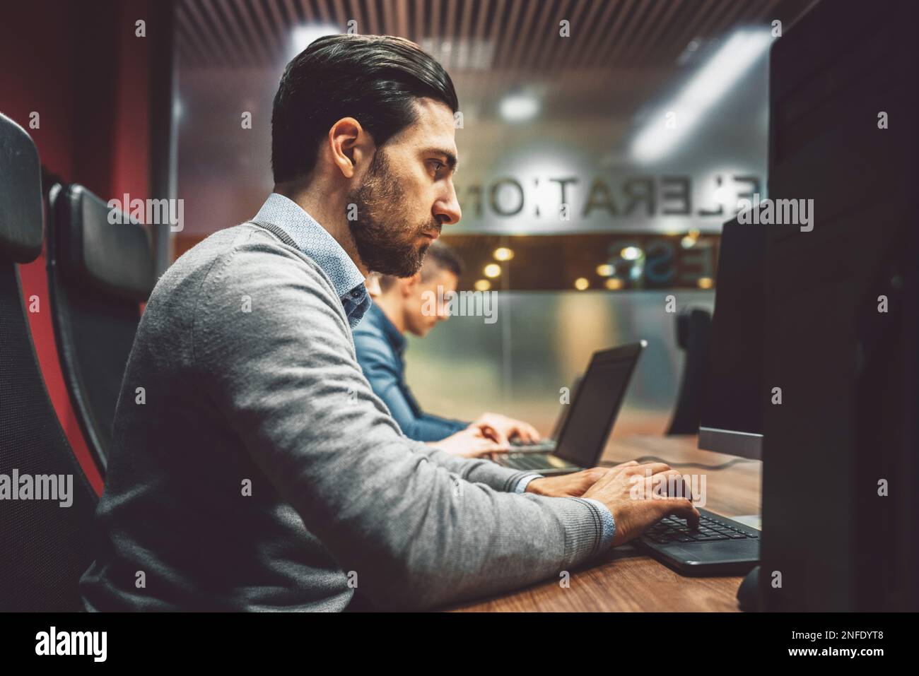 Side profile of a young tech man working on computer in the office ...