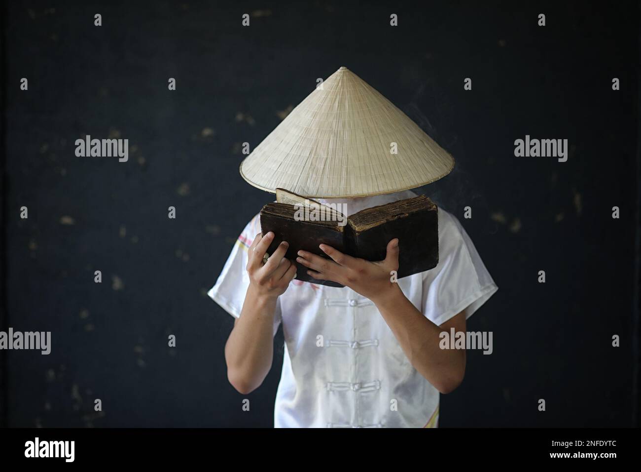 Asian young monk in hat on black wall background Stock Photo - Alamy