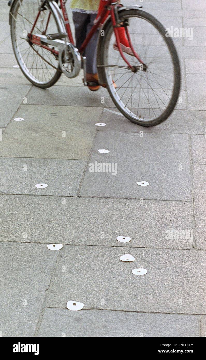 A bicycle rides past pieces of white paper cut in the shape of ancient ...