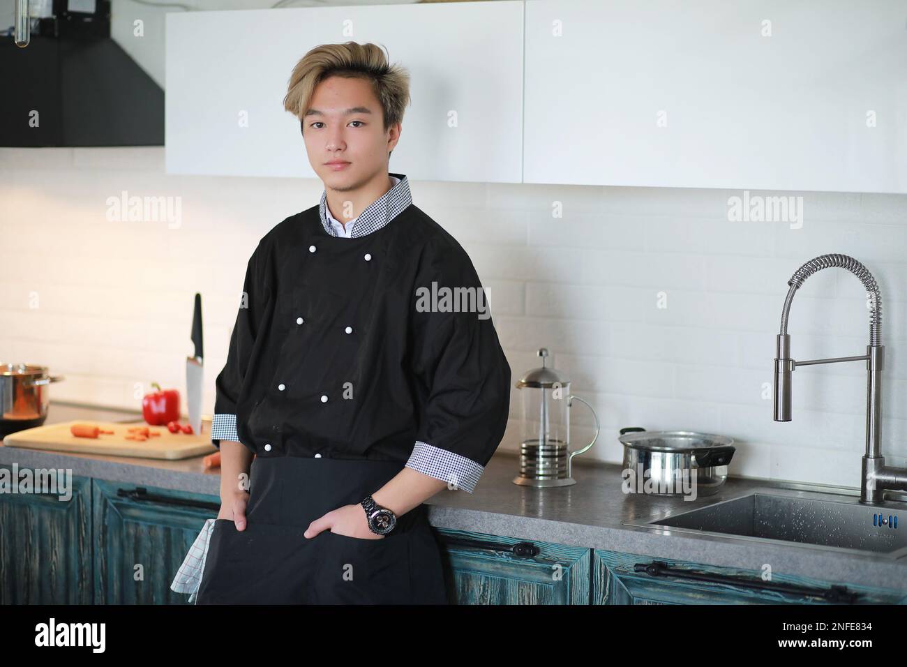 A young Asian cook in the kitchen prepares food in a cook suit Stock ...
