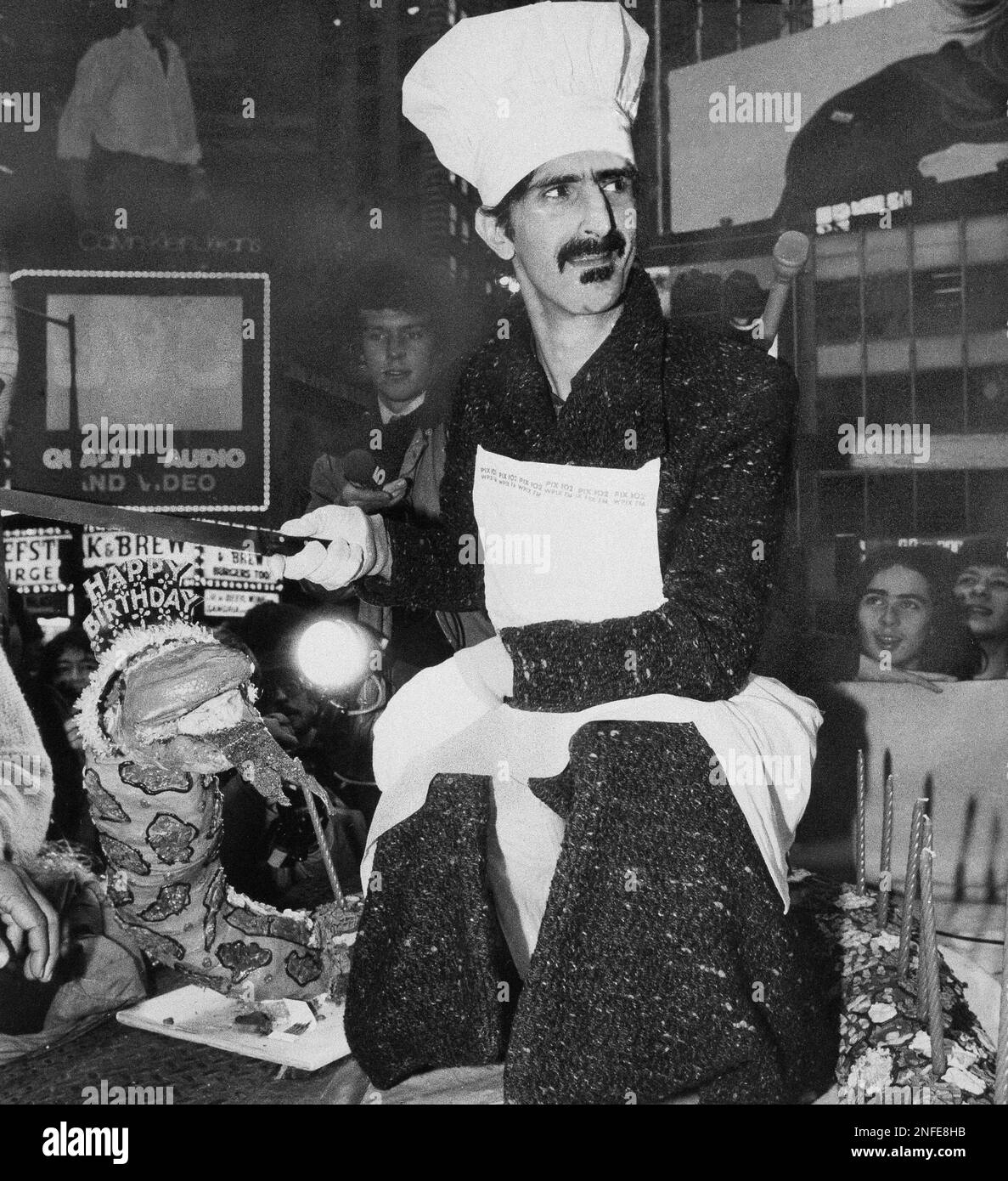 Rock star Frank Zappa, wearing a chef's cap, cuts a 20-foot-long cake ...