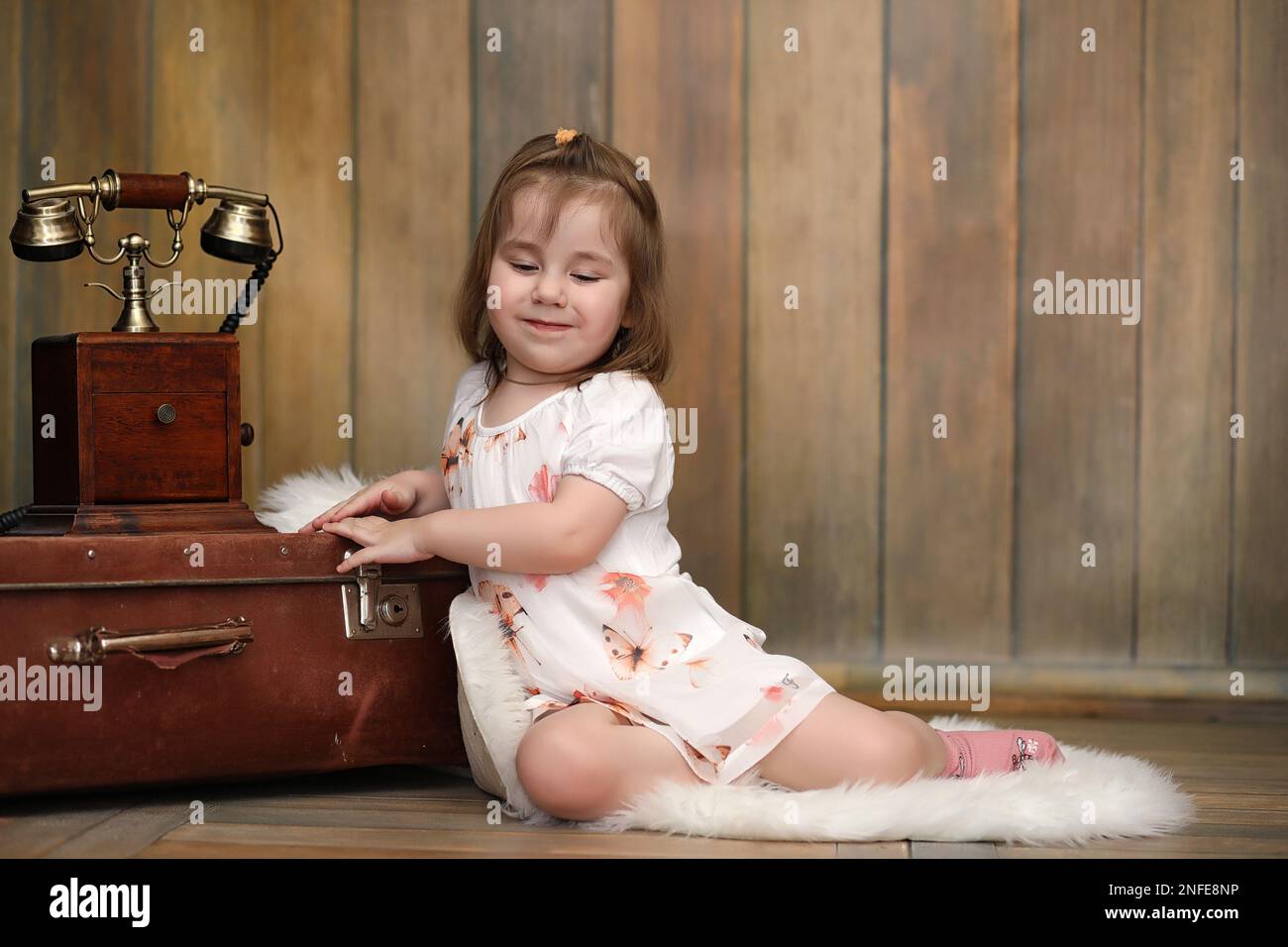 A child in a retro interior and an old phone sits on the floor. A small ...