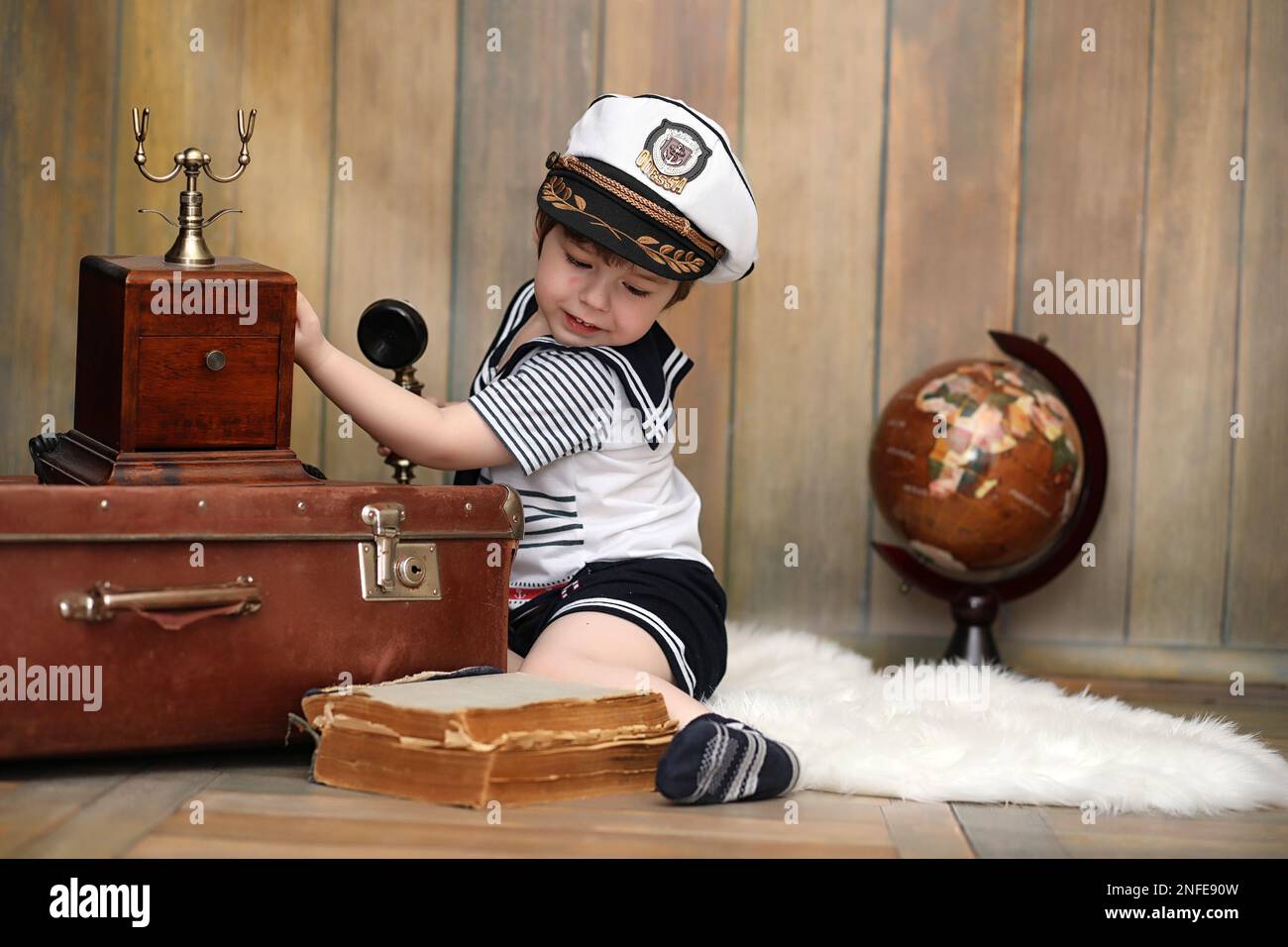 A child in a retro interior and an old phone sits on the floor. A small ...