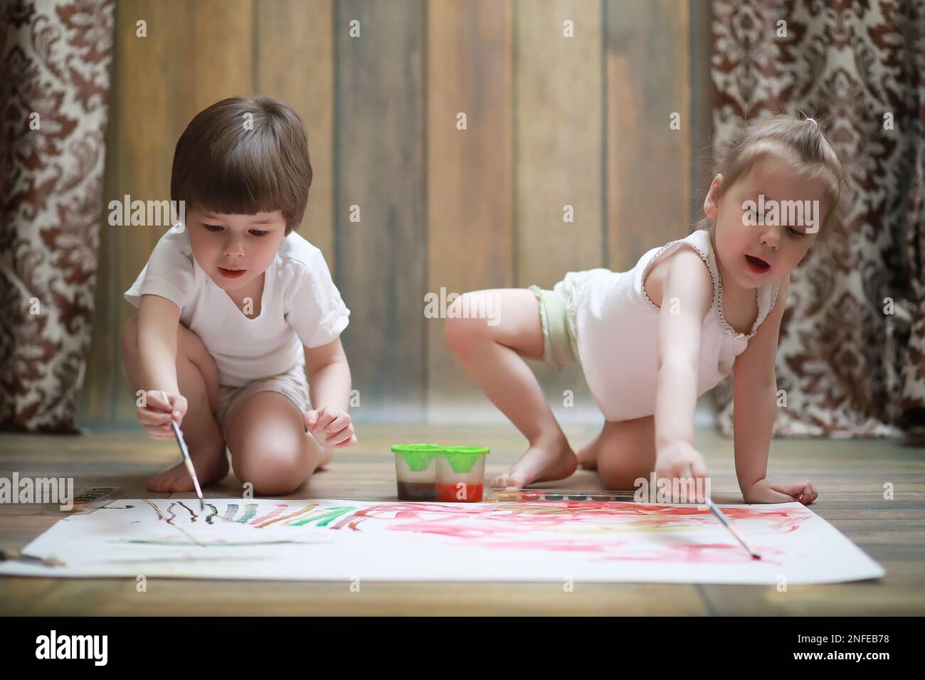 Little children paint on a large sheet of paper on the floor Stock ...