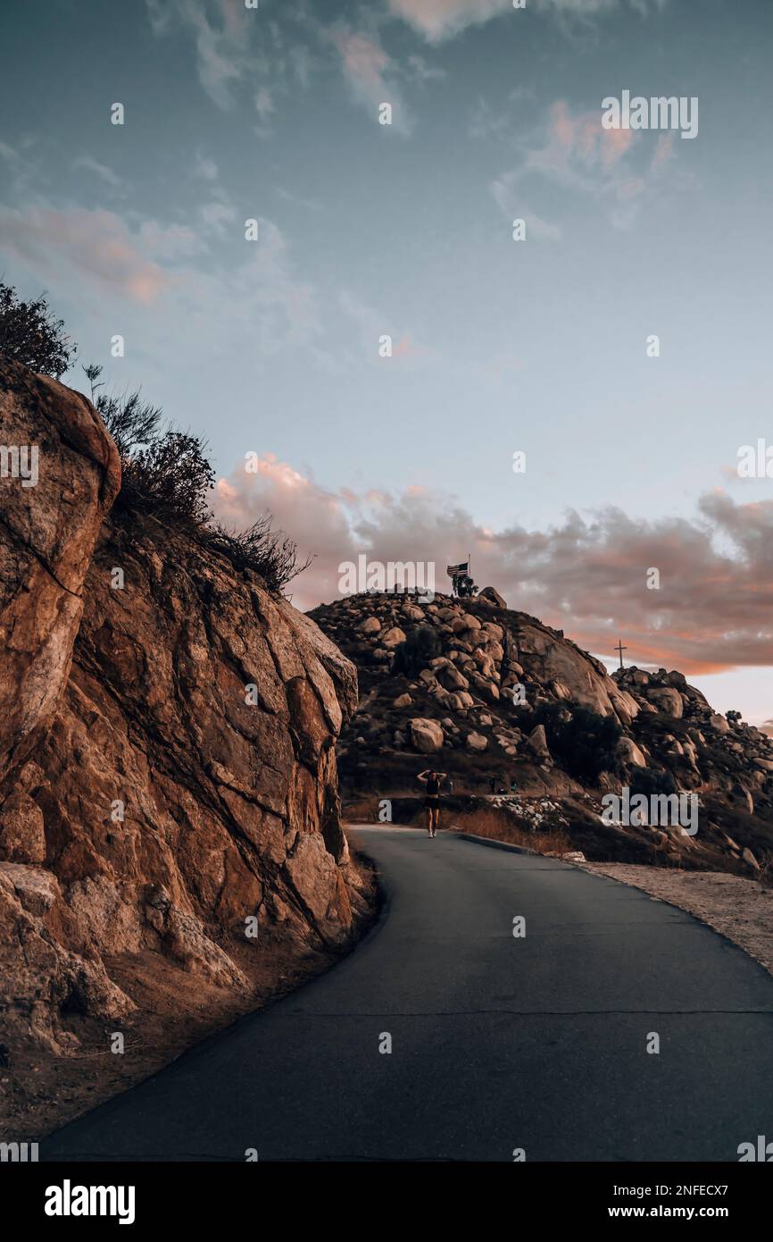 An expansive road extending down a steep hill with a cloudy sky in the ...