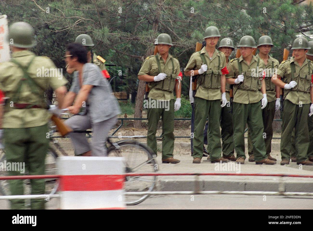Chinese troops watch as residents cycle by in the streets of Beijing ...