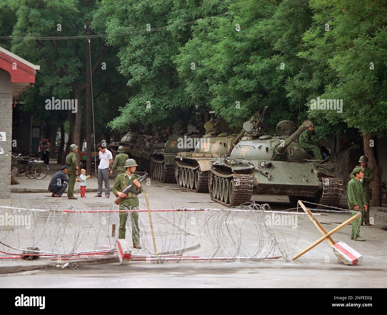 People's Liberation Army troops and tanks guard the street adjacent to ...