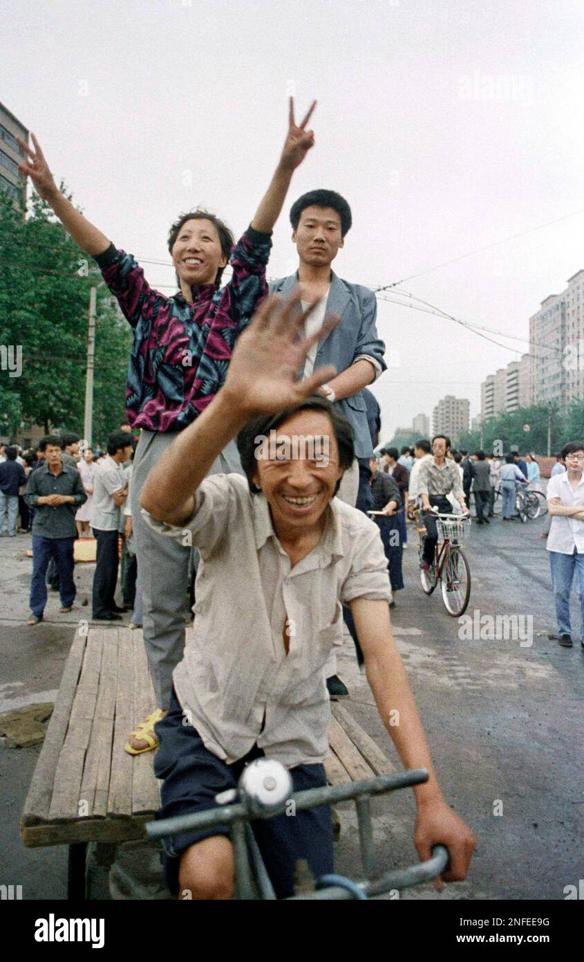 Local residents stand atop a rickshaw and flash victory-signs in ...