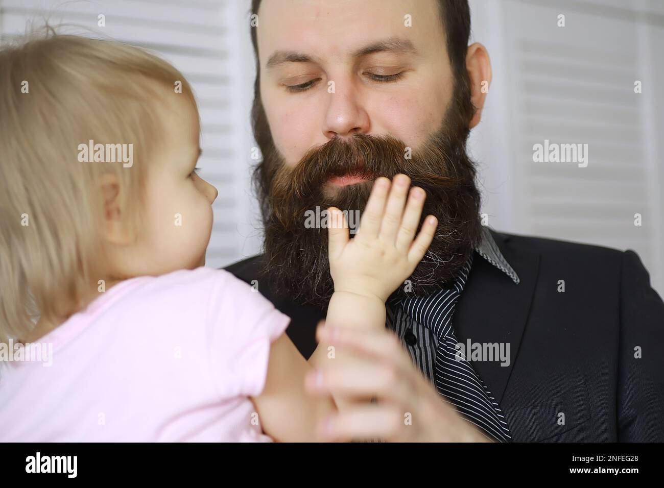 Baby infant hands grab beard of man.Cheerful hipster man curlers in a ...