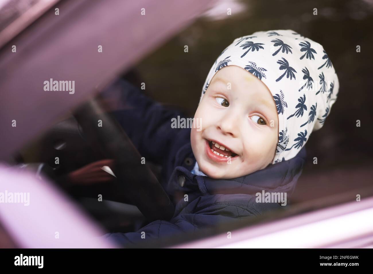 Little boy playing with a steering wheel in a car. Hands of a small ...