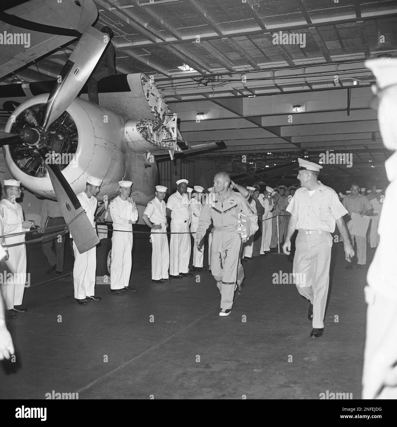 John Glenn leaves sick bay and walks across hangar deck of the USS ...