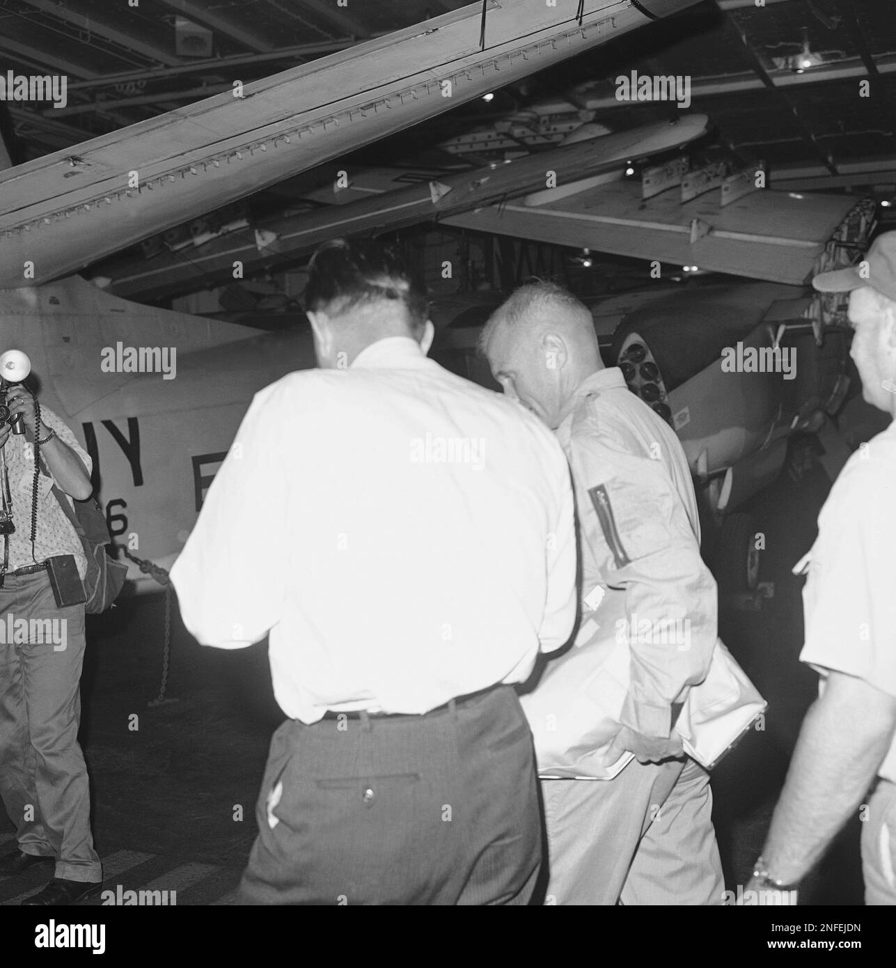 John Glenn leaves sick bay and walks across hangar deck of the USS ...