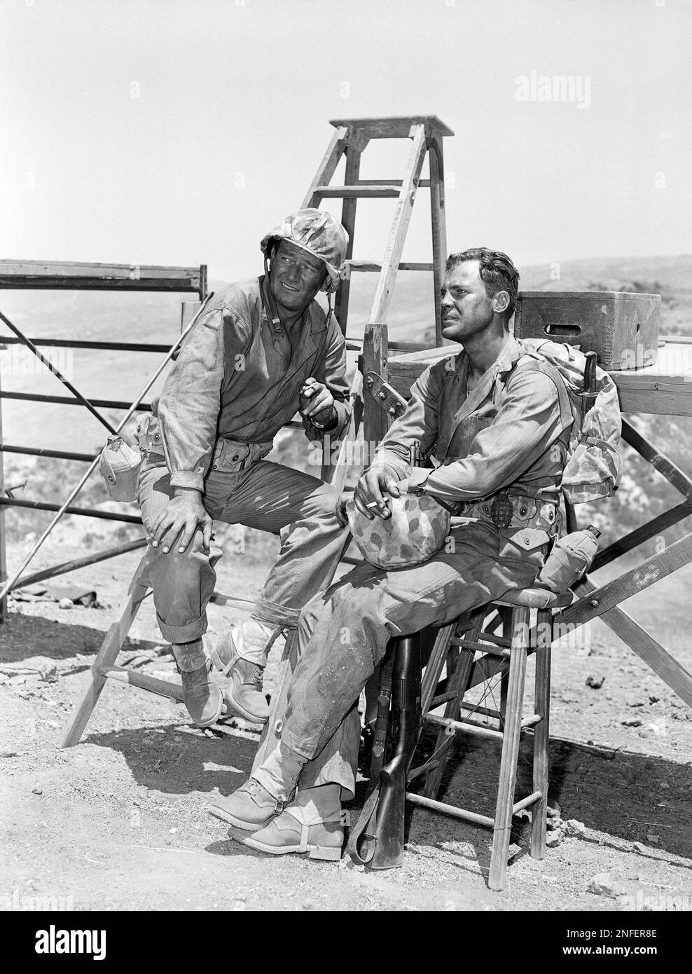 Movie actors John Wayne (left) and John Agar rest during filming of ...