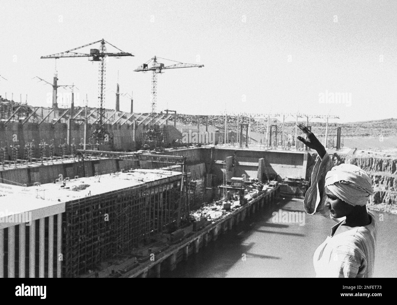 A young Egyptian worker, wearing a turban, waves as he stands on top of ...