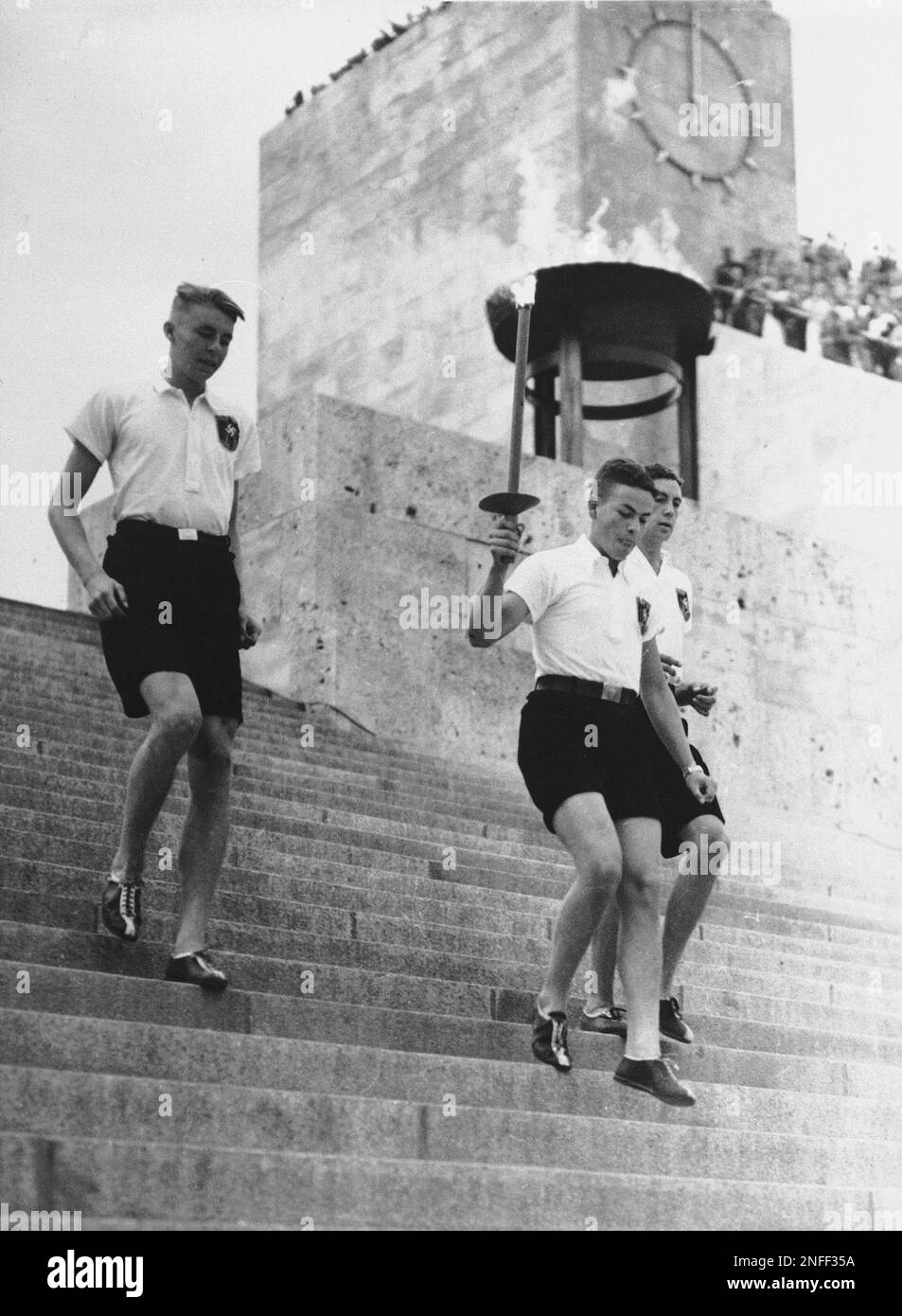 The Olympic flame is carried by a torch bearer from the Olympiastadion ...