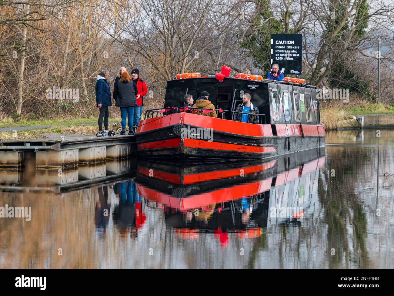People on towpath and in houseboat refelcted in water on Union Canal ...
