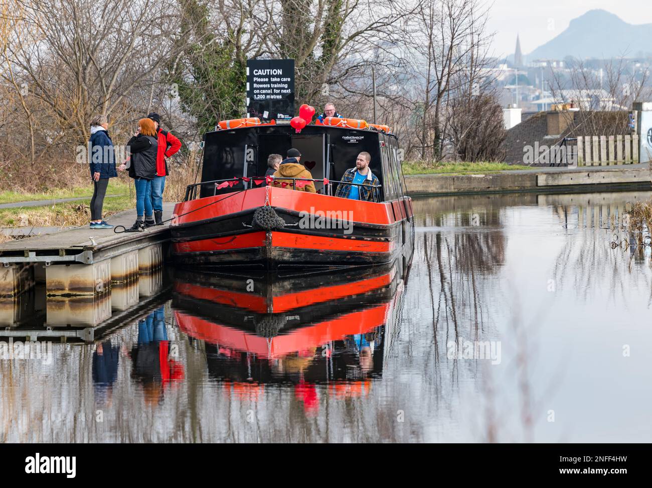 People on towpath and in houseboat refelcted in water on Union Canal ...
