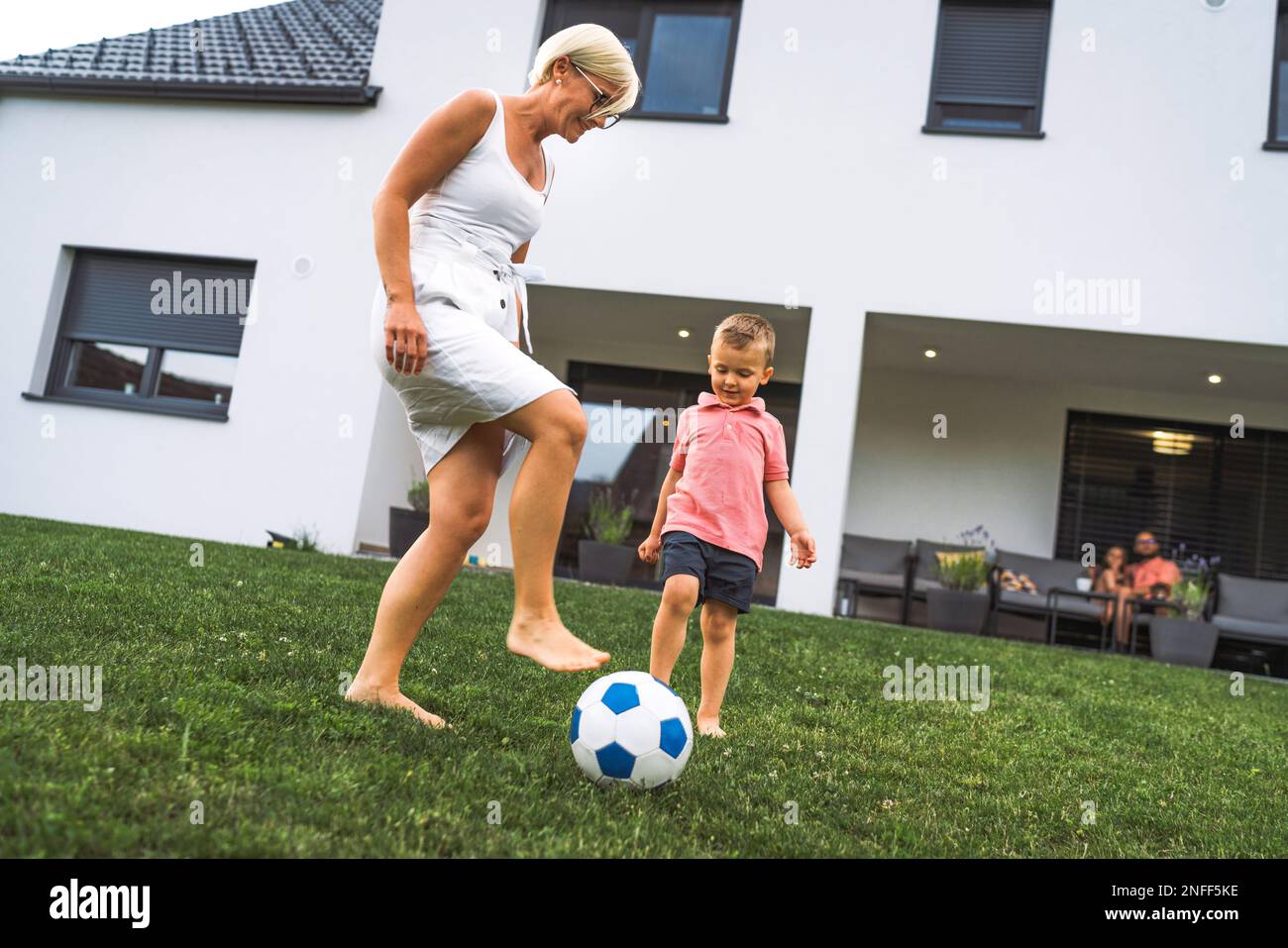 Mom playing football with her son outside the house on the grass Stock ...