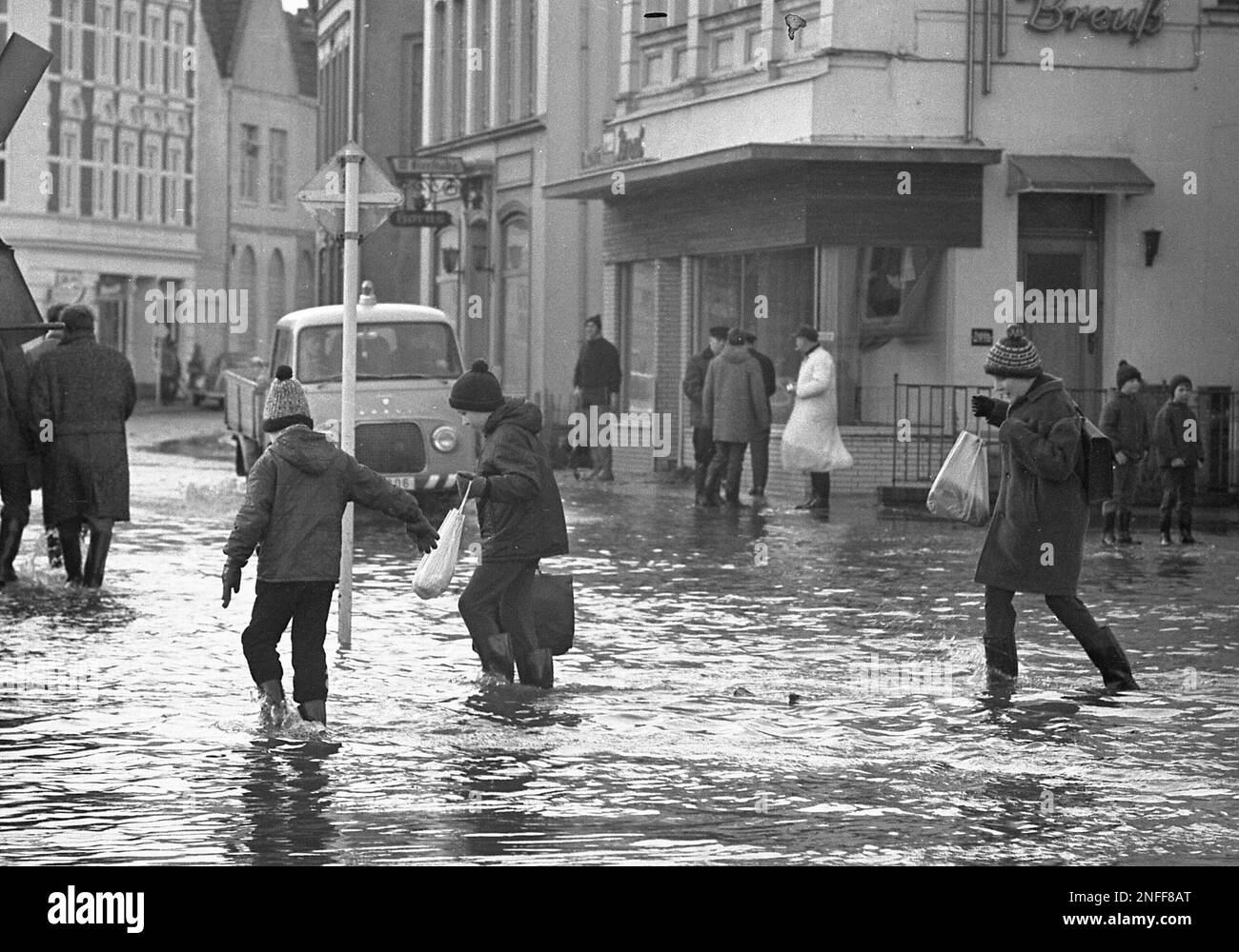 Pedestrians wades through the flooded streets of Elmshorn, West Germany ...