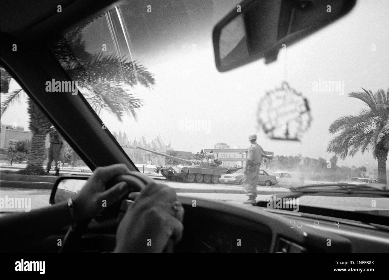 An Iraqi soldier stands guard as a tank patrols the streets of Kuwait ...