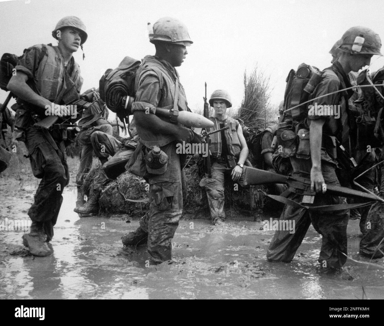 American Marines wade calf-deep through mud and water as they leave on ...