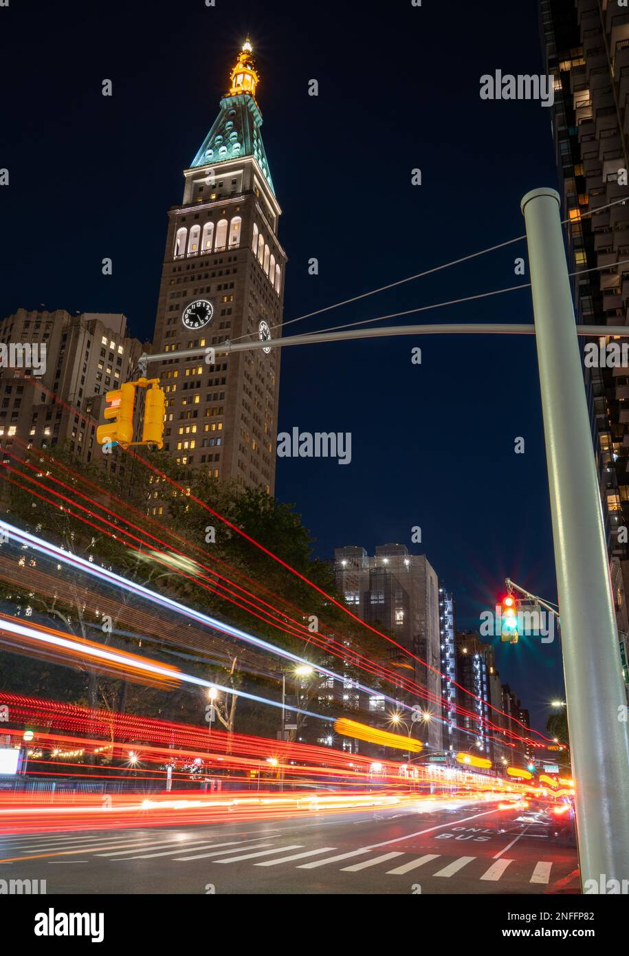An illuminated NYC street at night, with multiple street lights casting ...